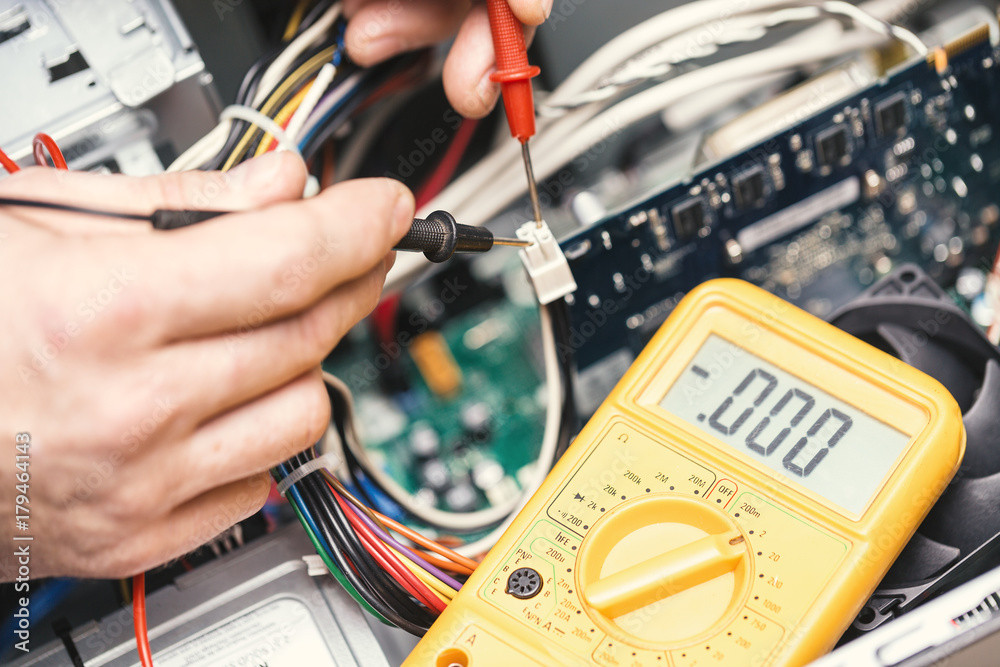 Technician hands with voltmeter above computer motherboard. Repair of ...
