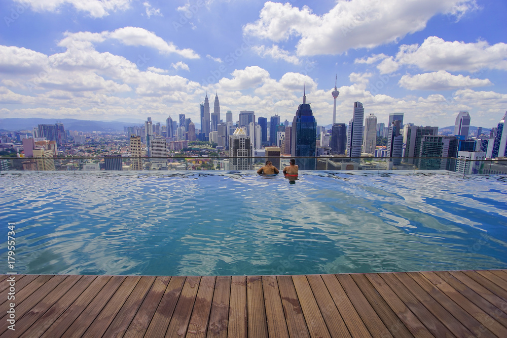 Unidentified businessman and traveller swimming in infinity pool with ...