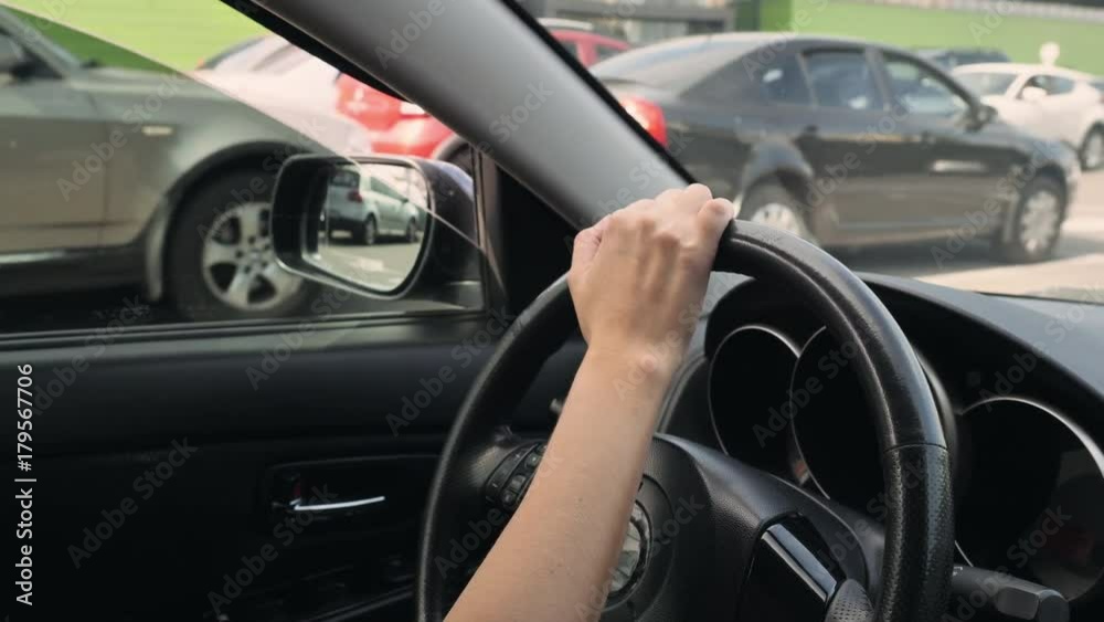 woman driving car on the parking lot. Female drives past building with ...