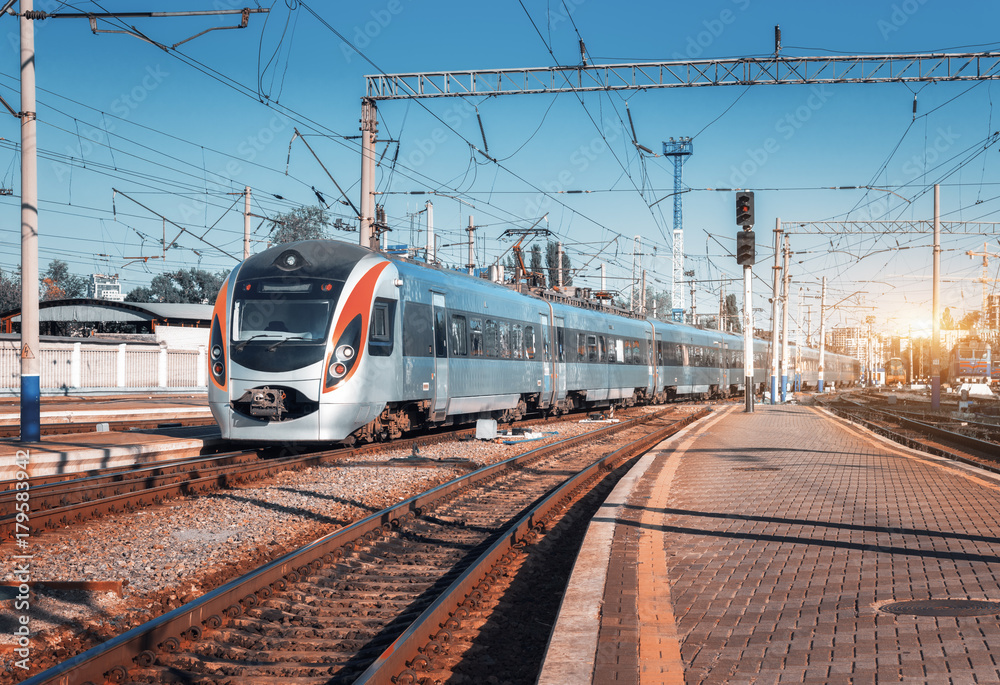 High speed train arrives on the railway station at sunset in Europe ...