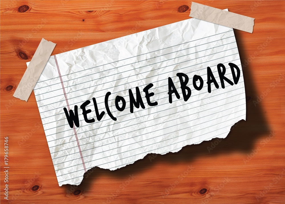 WELCOME ABOARD handwritten on torn notebook page crumpled paper on wood ...