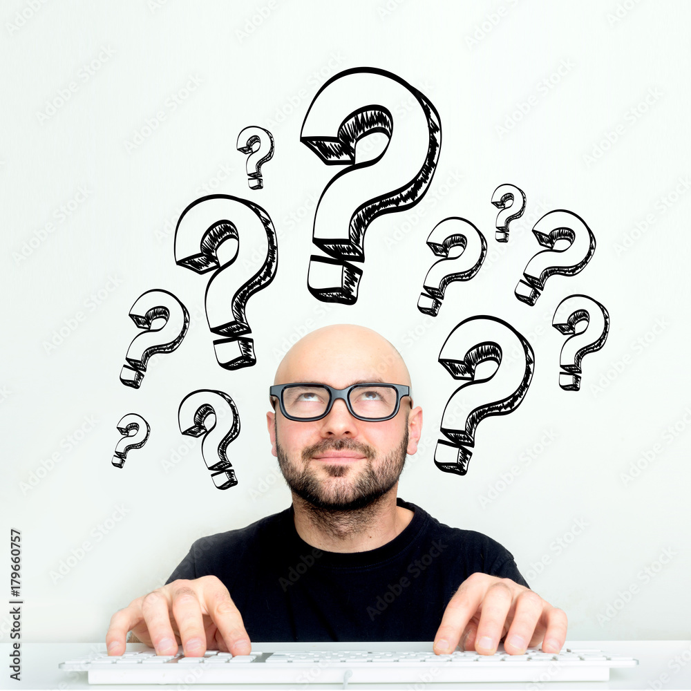 Portrait of an attractive stressed geek man with question mark icons ...