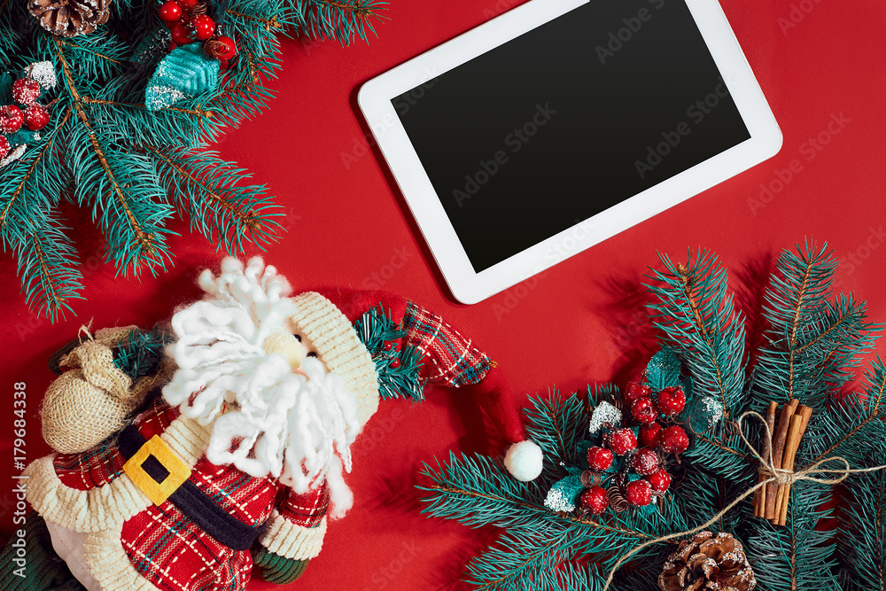 Christmas decorations and white tablet with black screen on hot red ...