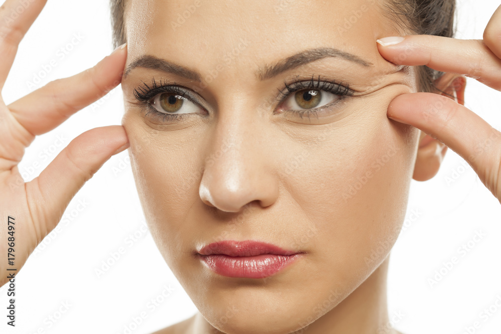 young women pinching her wrinkles next to her eyes with her fingers ...