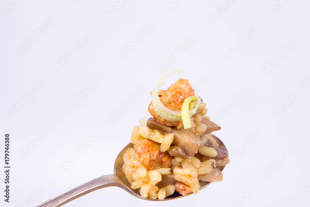 Risotto with mushrooms and chicken decorated with leek on a spoon on a ...