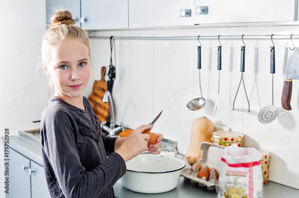 Little cook girl breaks eggs in a deep dish Stock Photo | Adobe Stock