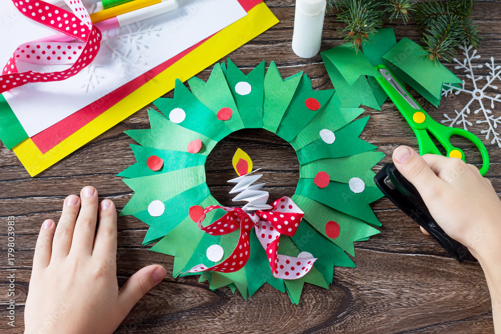 The child is laying the details of the Christmas wreath with a candle ...