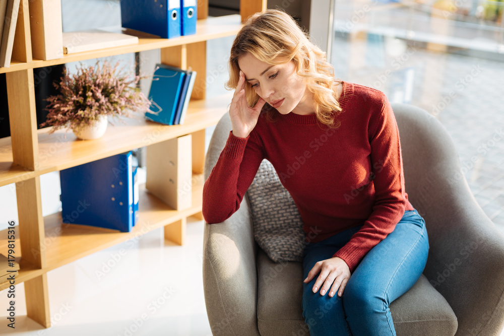 Difficult times. Unhappy pleasant young woman holding her forehead and ...