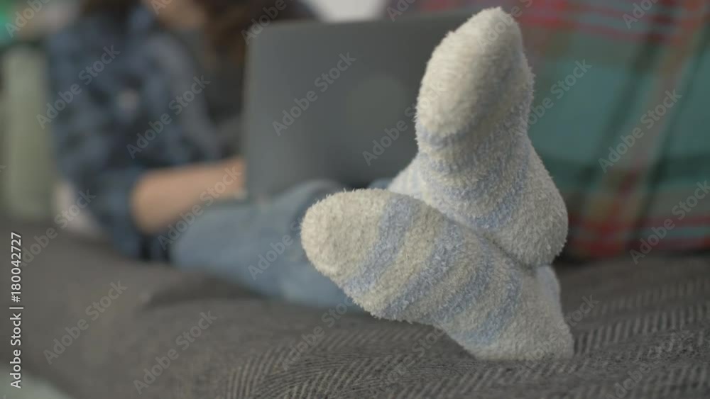 Woman Wearing Socks While Using Laptop On Sofa Stock Video | Adobe Stock
