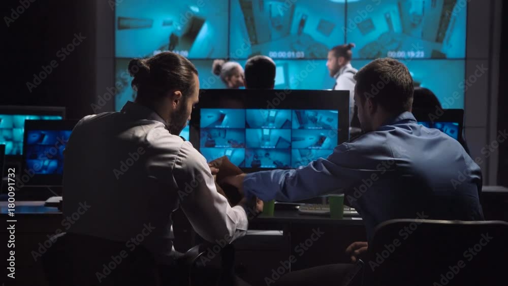 Security guards eating donuts while watching the surveillance cameras ...