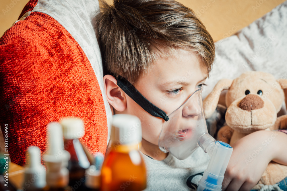 child holds a mask vapor inhaler. breathing through a steam nebulizer ...