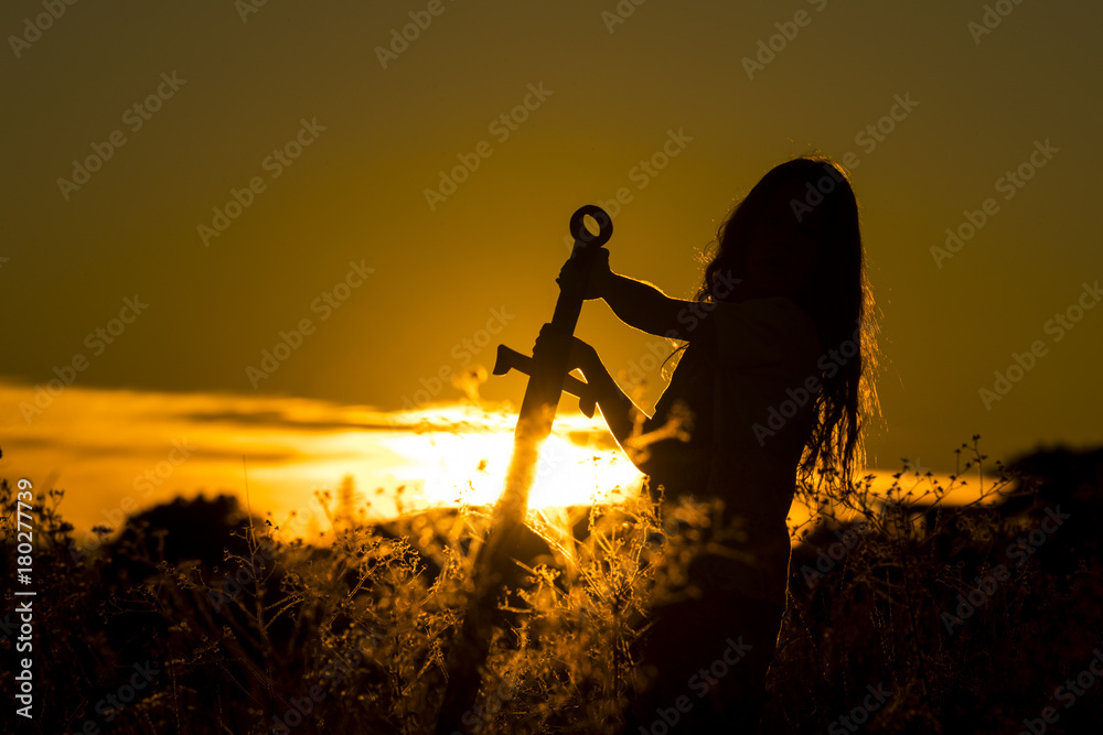 Boy pulling up a sword with the setting sun in the background Stock ...