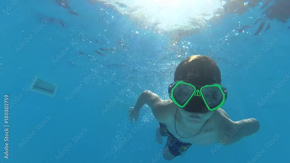 Boy dive in swimming pool and looking at the camera, underwater shoot ...