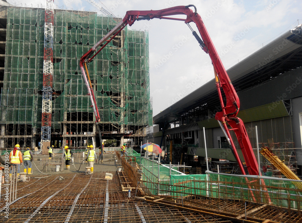 Construction workers pouring wet concrete using concrete hose from ...