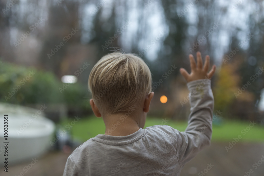 Little boy standing staring out of a window Stock Photo | Adobe Stock