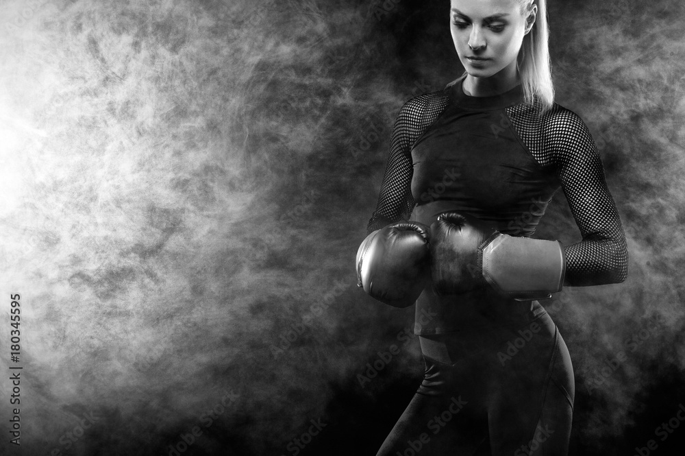 A strong athletic, woman boxer, boxing at training on the black ...