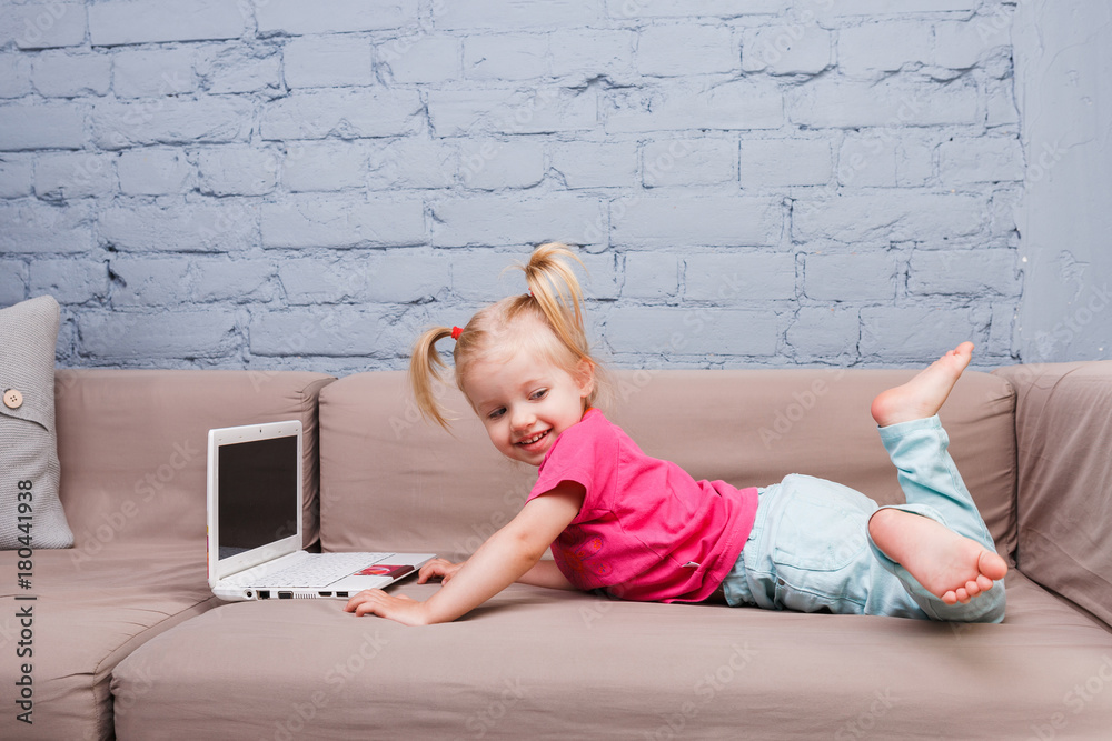 Beautiful funny blonde girl a child of two years is lying on the couch ...