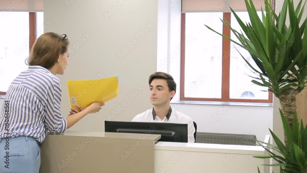 Video Stock Woman Asks Man At Reception To Send Important Documents For Management In Office video-stock-woman-asks-man-at-reception-to-send-important-documents-for-management-in-office