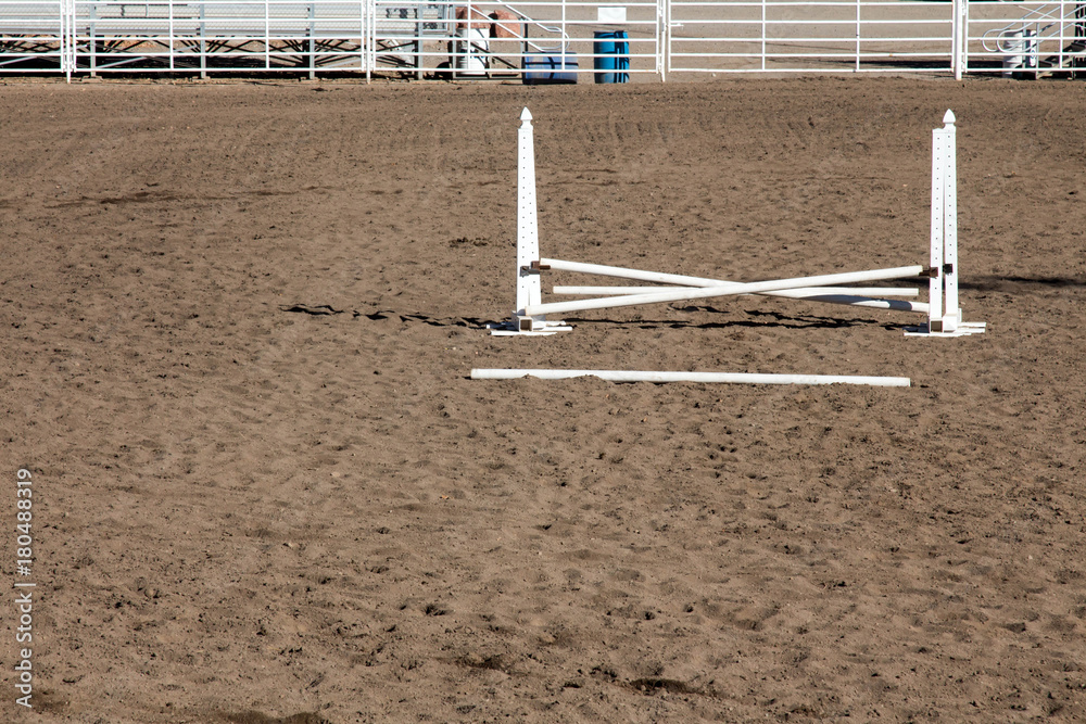 Single white horse jumping ring at a county fairgrounds with fallen ...
