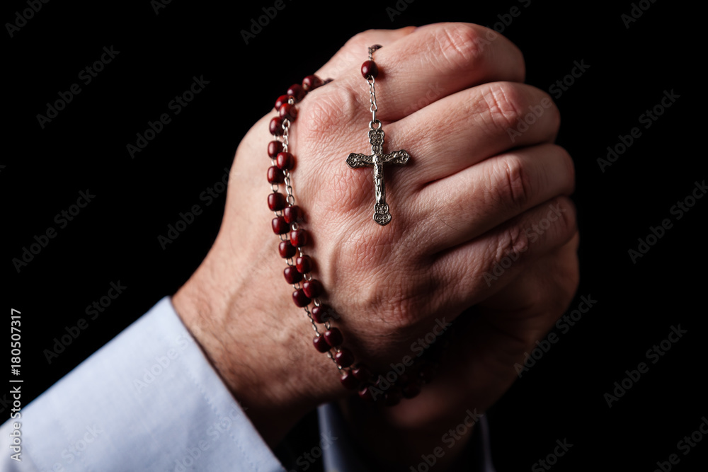 Male hands praying holding a rosary with Jesus Christ in the cross or ...