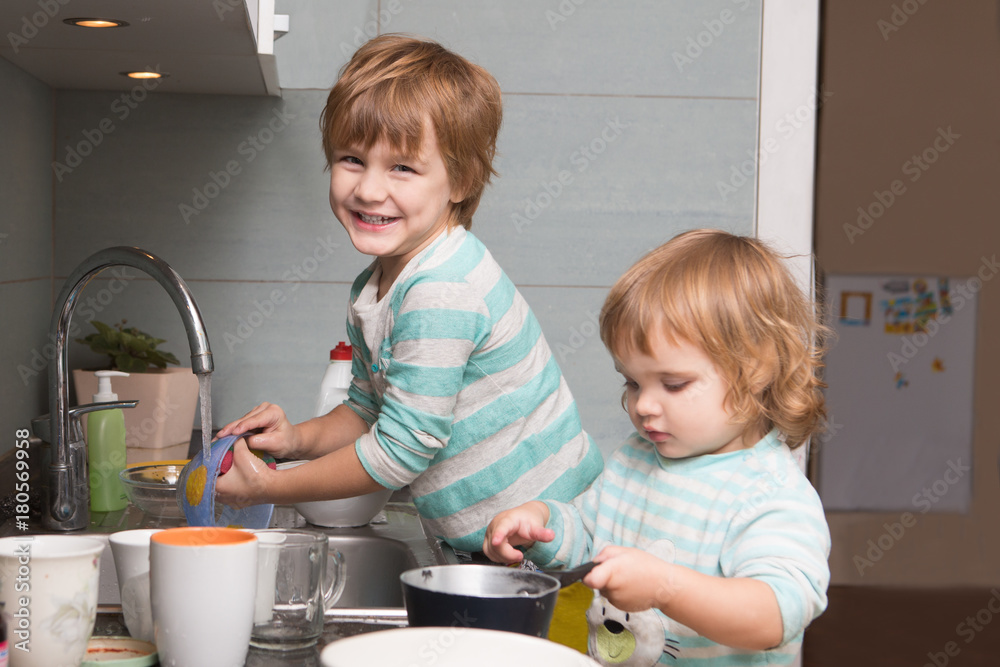 Poster A little cute children washing dishes in the white kitchen ...