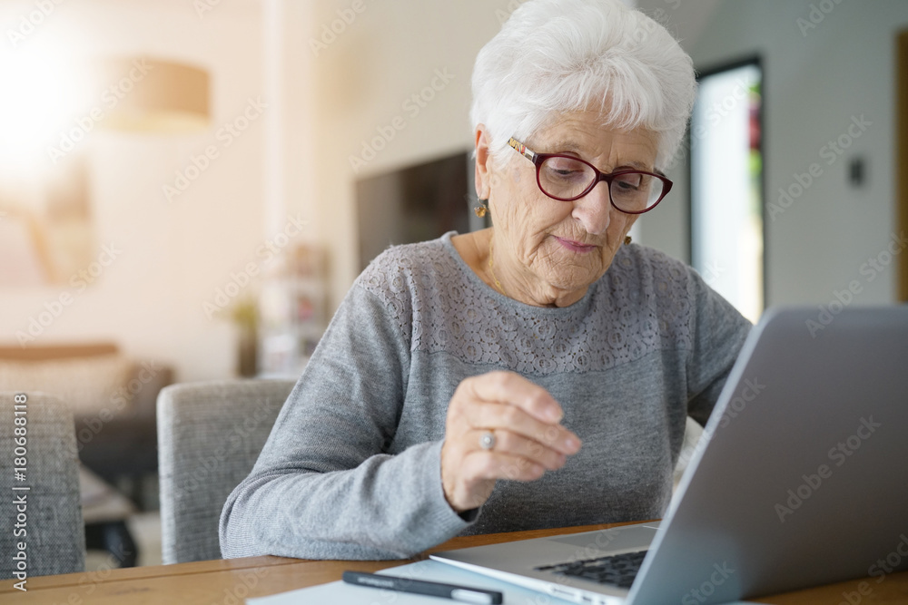 Old woman at home using laptop computer Stock Photo | Adobe Stock