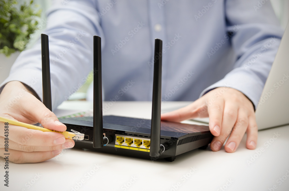 Man plugs Ethernet cable into router. router wireless wire broadband ...