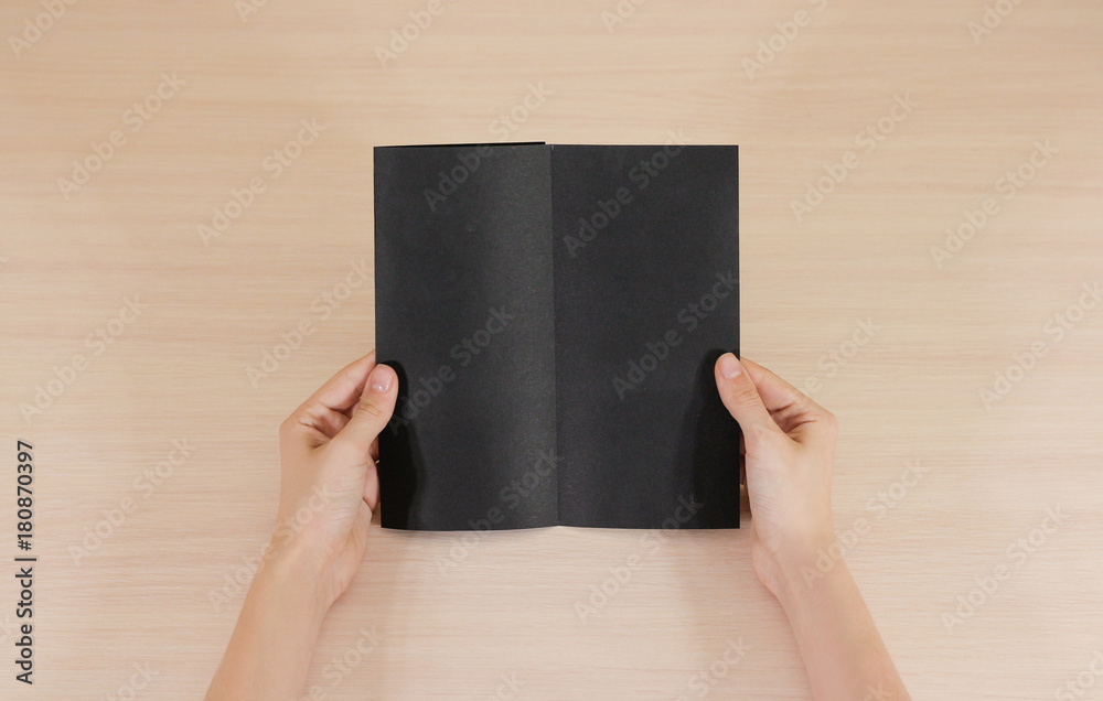 Hands holding blank black brochure booklet in the hand. Leaflet ...