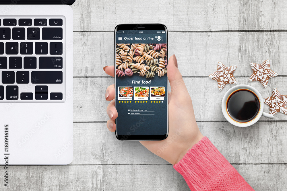 Female hand holding phone with food ordering app on white wooden desk ...