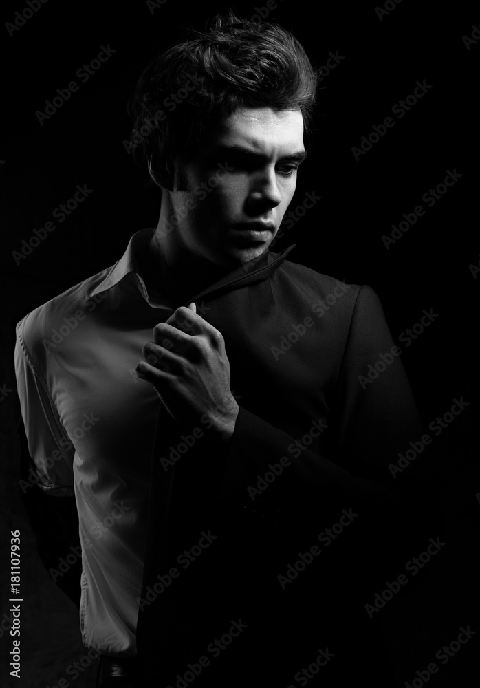 Handsome charismatic emotional man looking serious in dark shadow ...