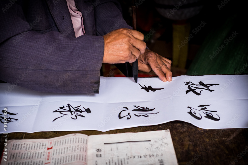 Man is writing with chinese idioms at Shigu Village or Stone Drum ...
