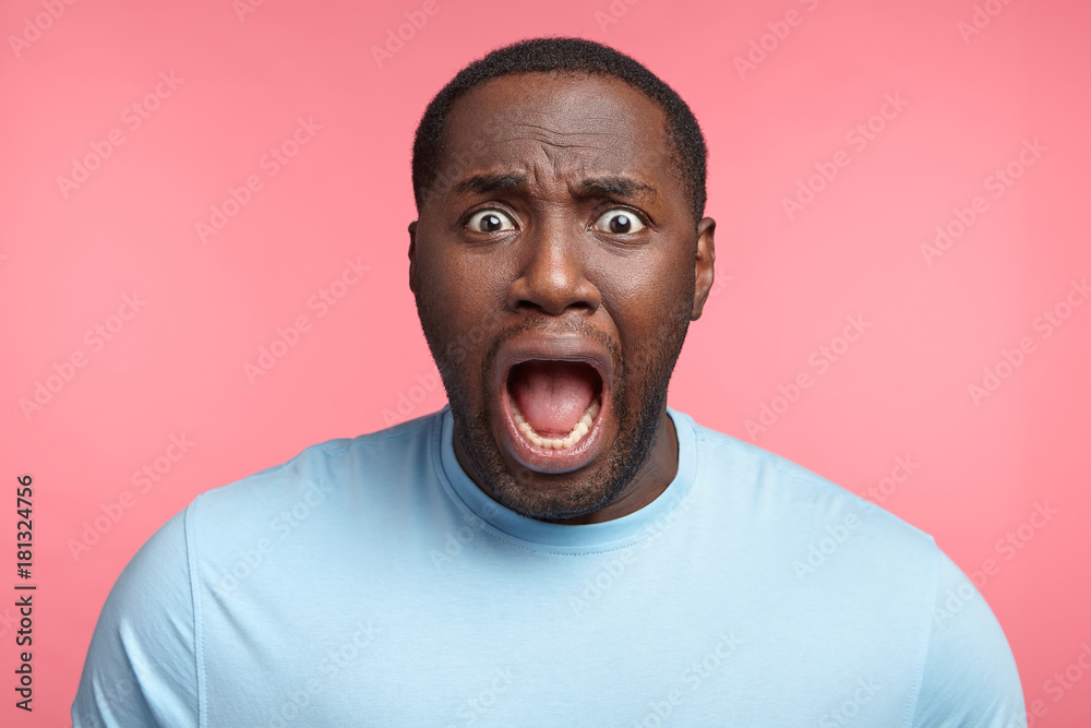 Excited African American man screams in panic, gaze with bugged eyes ...