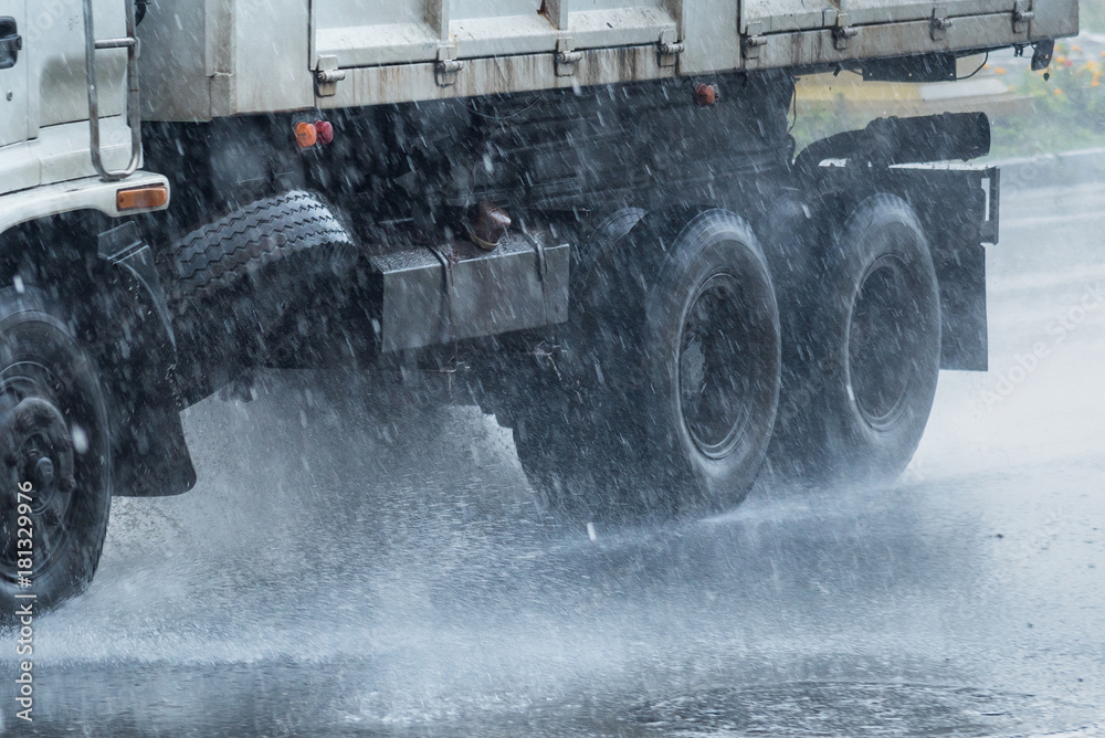 Rainwater spraying from motion truck wheels. city road during heavy ...