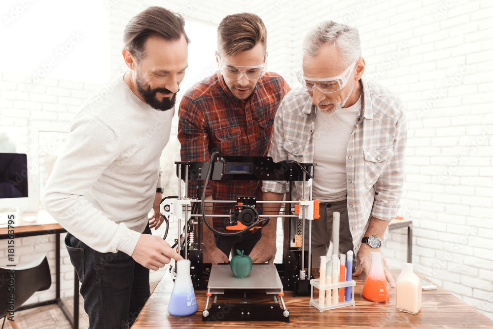 Three men are working to prepare printed on a 3d model printer. They ...
