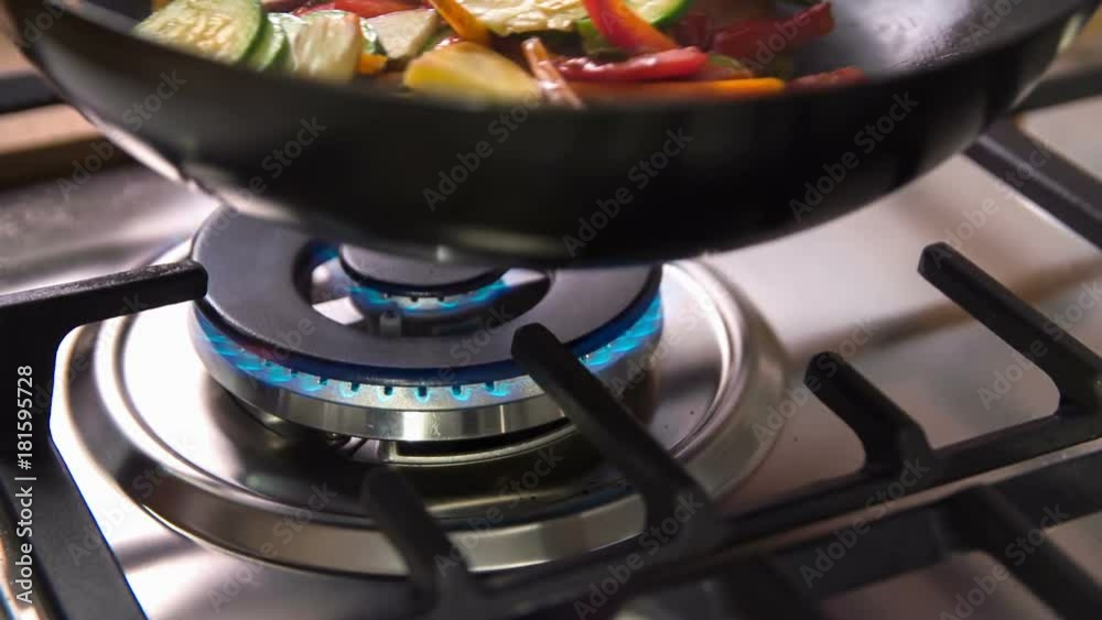 Cooking healthy and organic vegetables in a wok. Cook is turning wok ...
