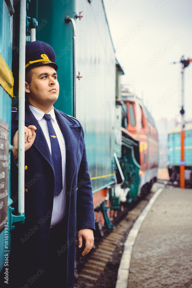 European or American train conductor is on his duty on a platform and ...
