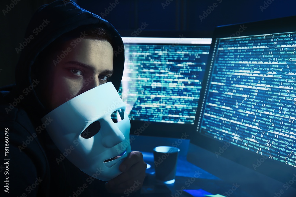 Hacker with mask near computer in dark room Stock Photo | Adobe Stock