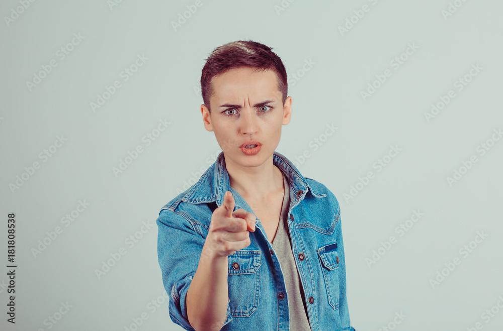 Portrait young; unhappy; serious woman pointing finger at someone ...