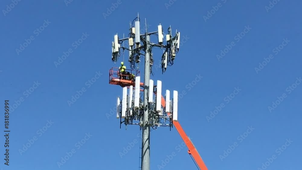 Men at work high on a boom lift fixing a cell tower with a flawless ...