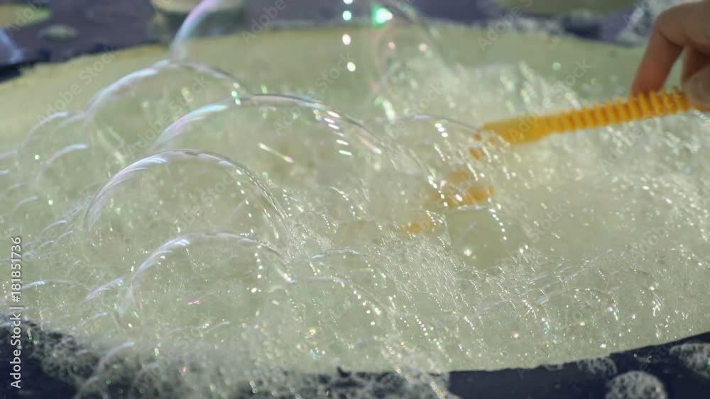 Close-up of soap bubbles at party. Hands put the rings into soapy ...