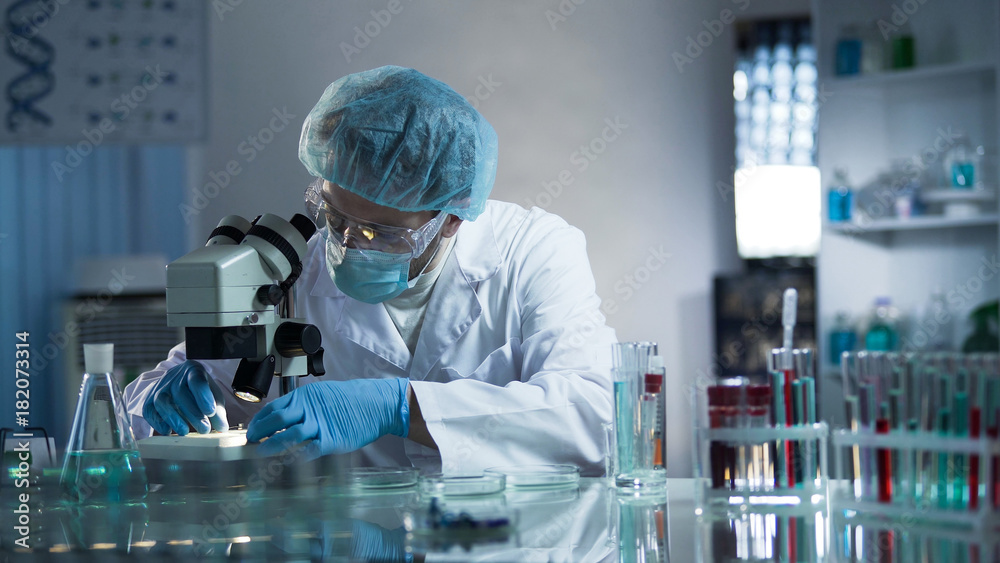 Medical lab worker examining laboratory glass with sample through ...