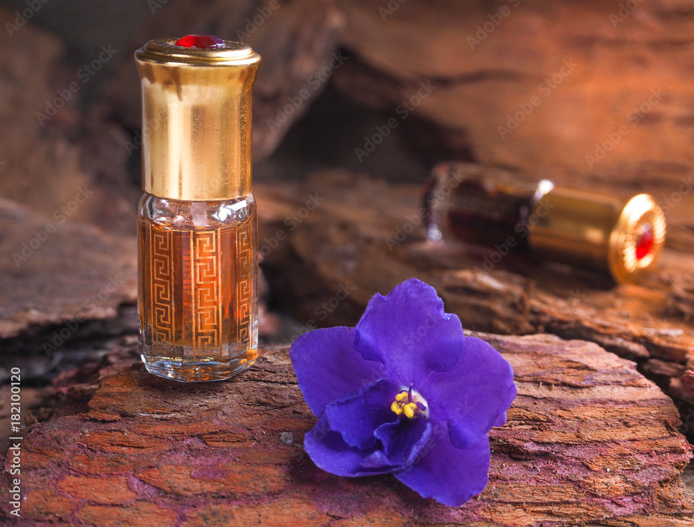 Bottle of oil agarwood tree against the bark. Arabian oud attar perfume ...