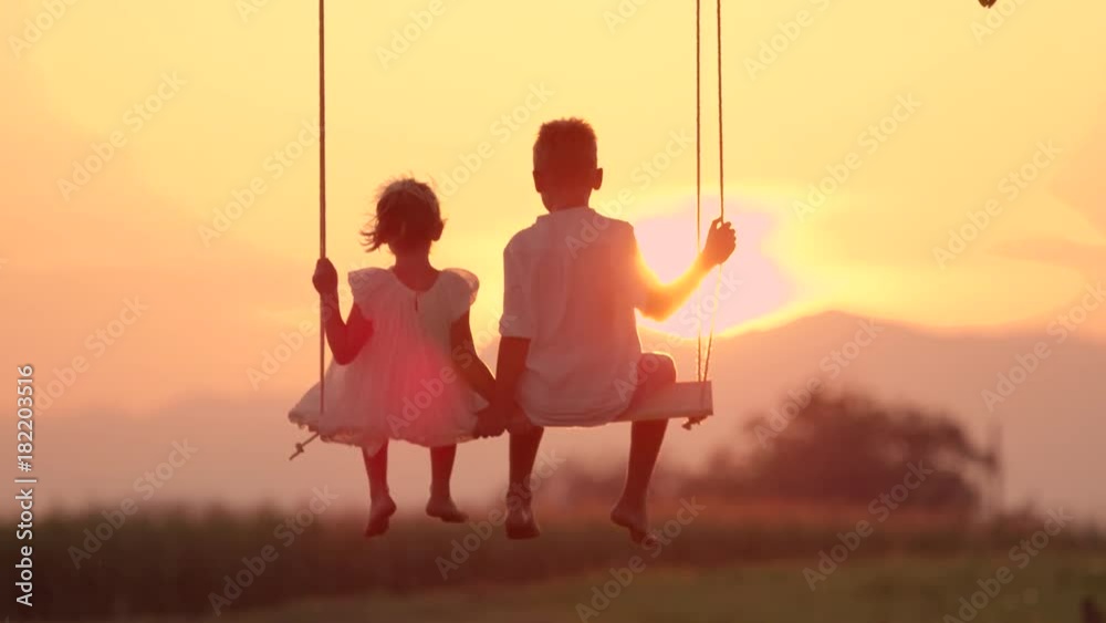 SLOW MOTION SILHOUETTE, LENS FLARE Two kids looking at sunset while ...