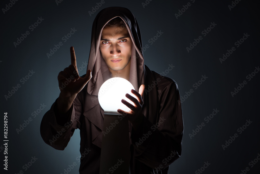 Young wizard with crystal ball in dark room Stock Photo | Adobe Stock