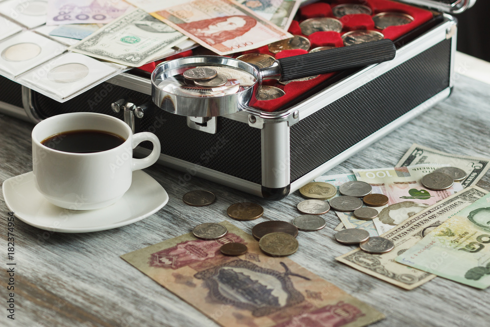 Different collector's coins and banknotes, cup of coffee and a ...