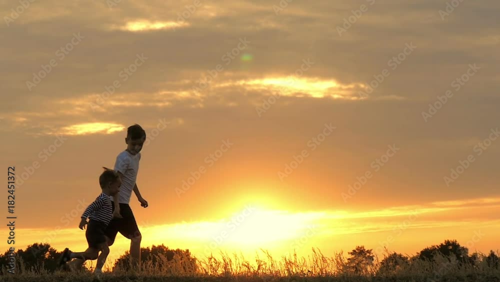 Two happy children running after each other against the sunset. The two ...