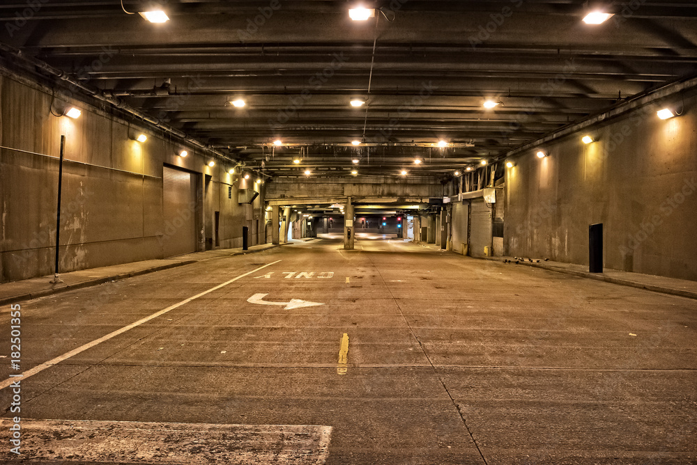 Dark and gritty downtown city street tunnel underpass at night in ...