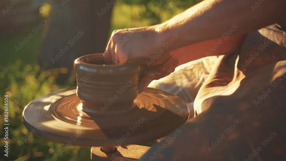 Close up view of craftsman’s hands creating a vessel, while moving a ...