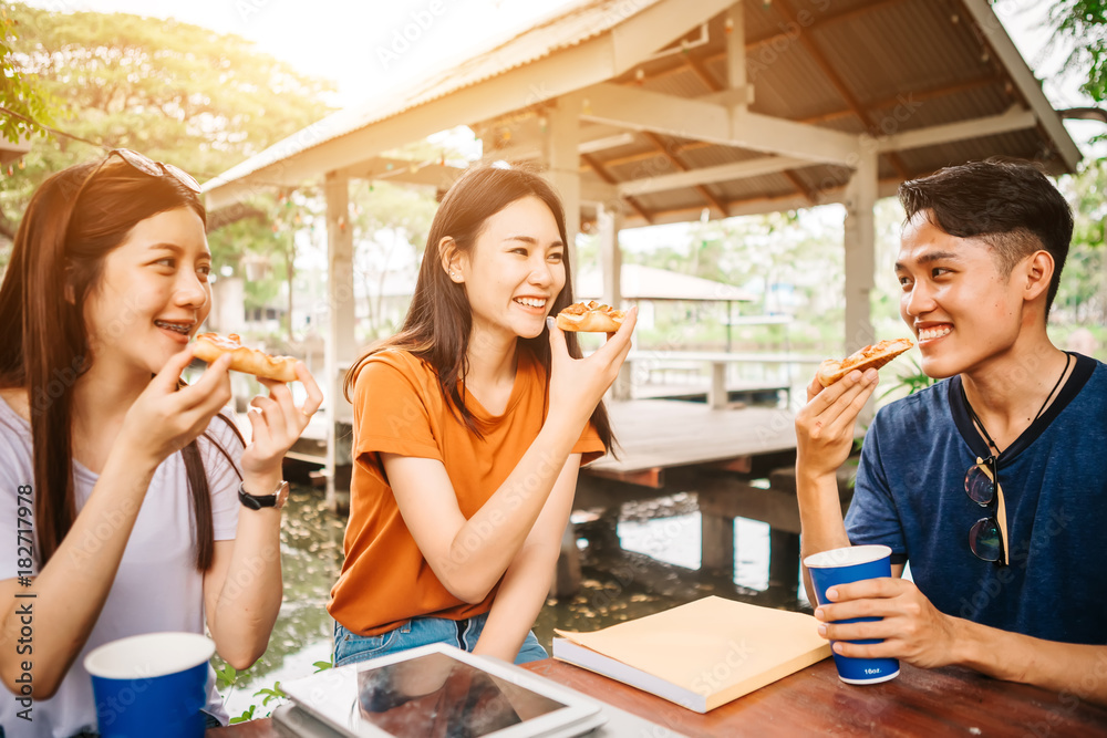 Asian students eating eating the pizza together in breaking time early ...