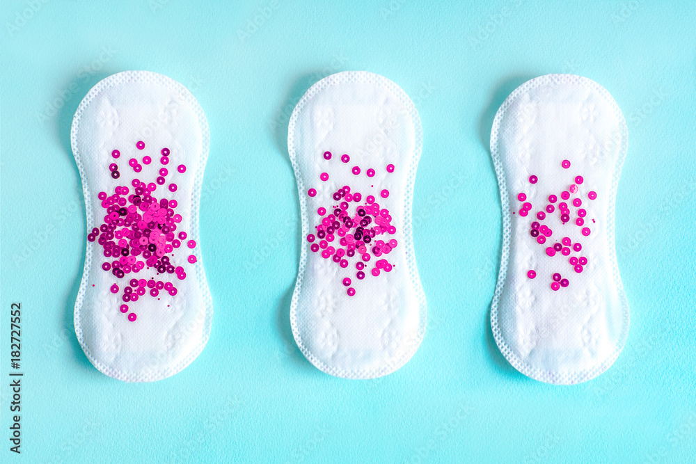Menstrual pad with bright purple glitter on blue colored background ...